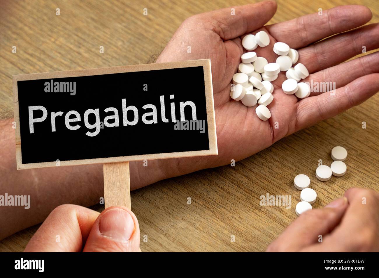 11 March 2024: Hand holding tablet in front of a hand with tablets ...