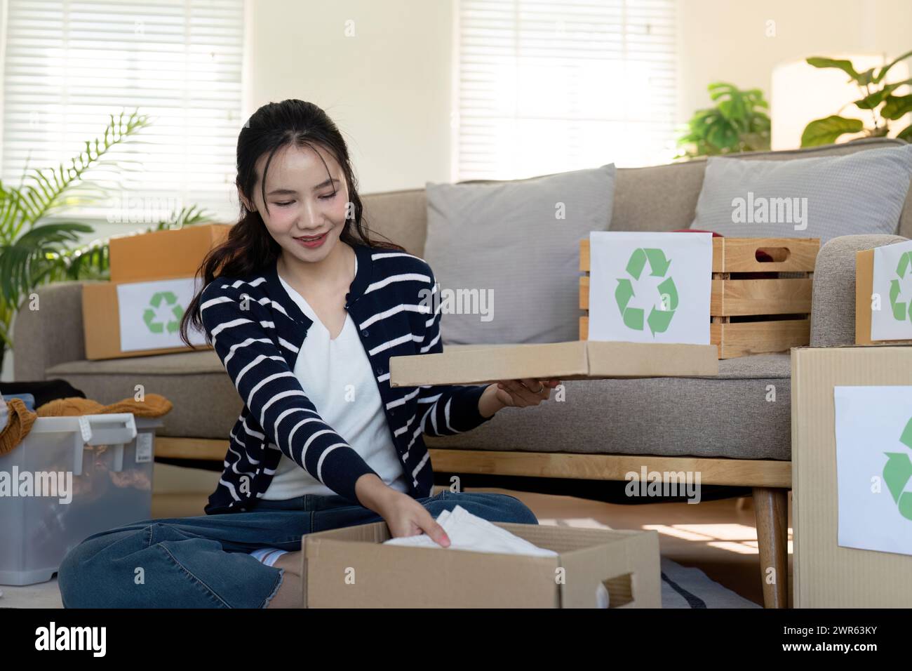 Woman pack box with used clothes for reuse. Reusing, recycling material ...