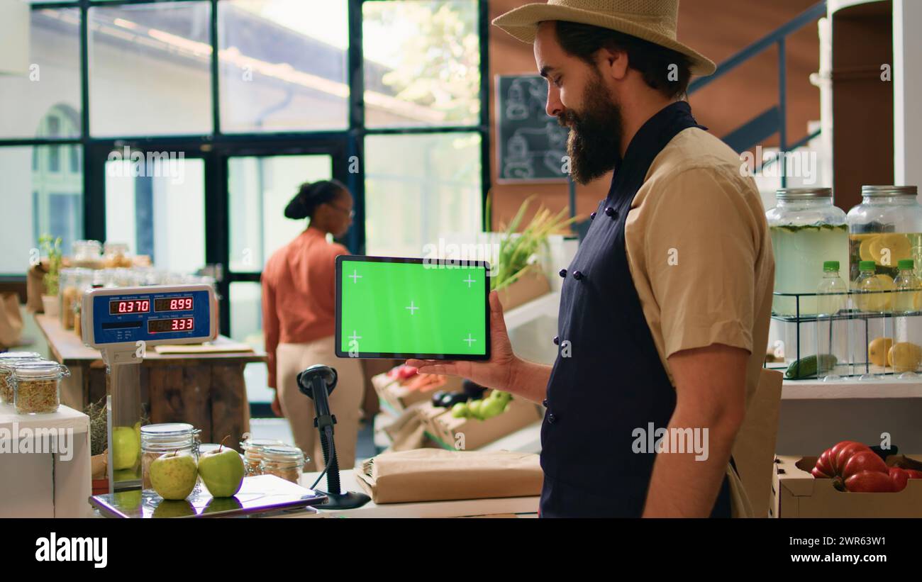 Storekeeper holds tablet with greenscreen in zero waste eco supermarket ...