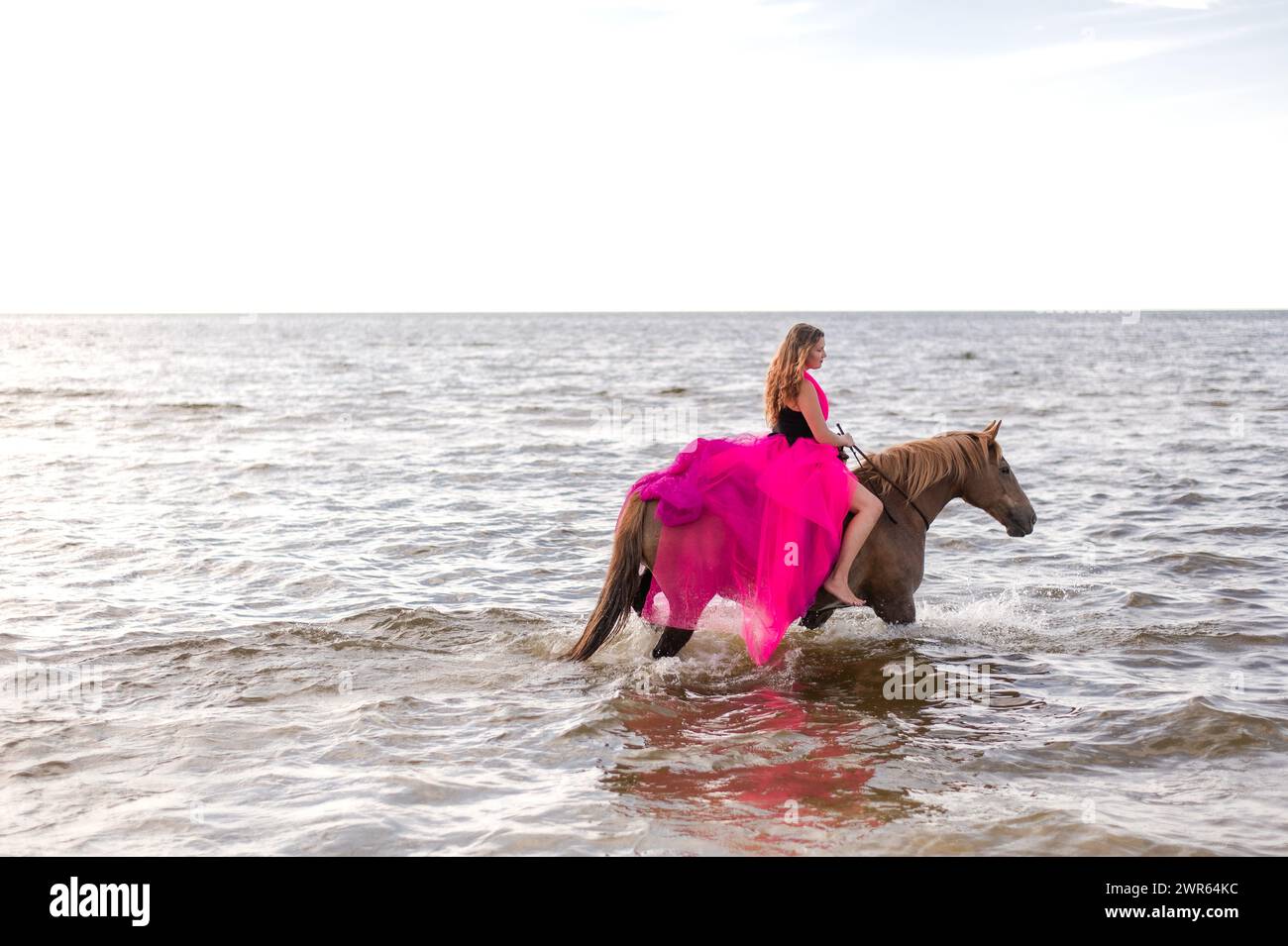 Woman in pink cape riding horse Stock Photo - Alamy