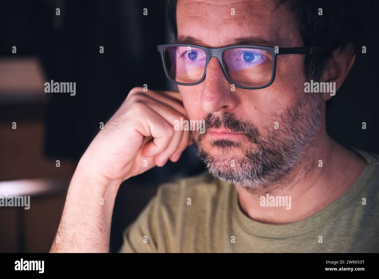 Man with eyeglasses looking at computer screen in dark room, reflection ...