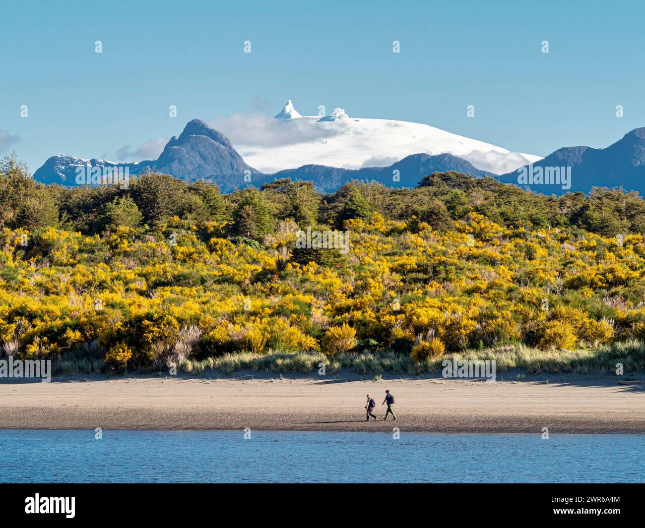 Tourists walk at the beach at Raul Marin Balmaceda, snowcovered volcano ...