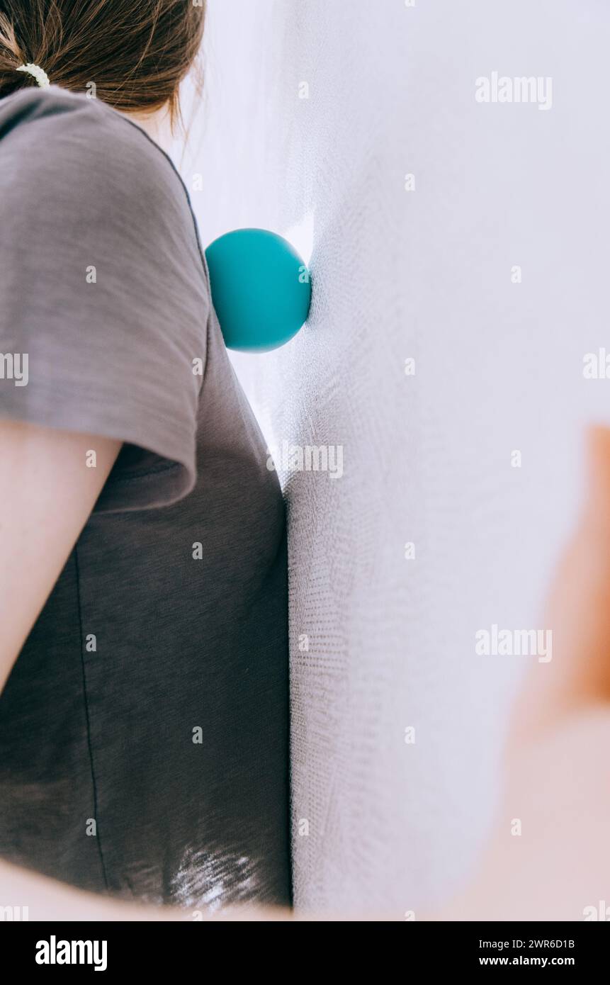 Woman doing pecs MFR exercise with therapy massage ball at the wall ...