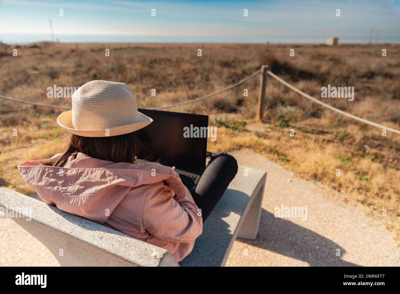 Woman with laptop computer sitting in front of the beach in Barcelona ...