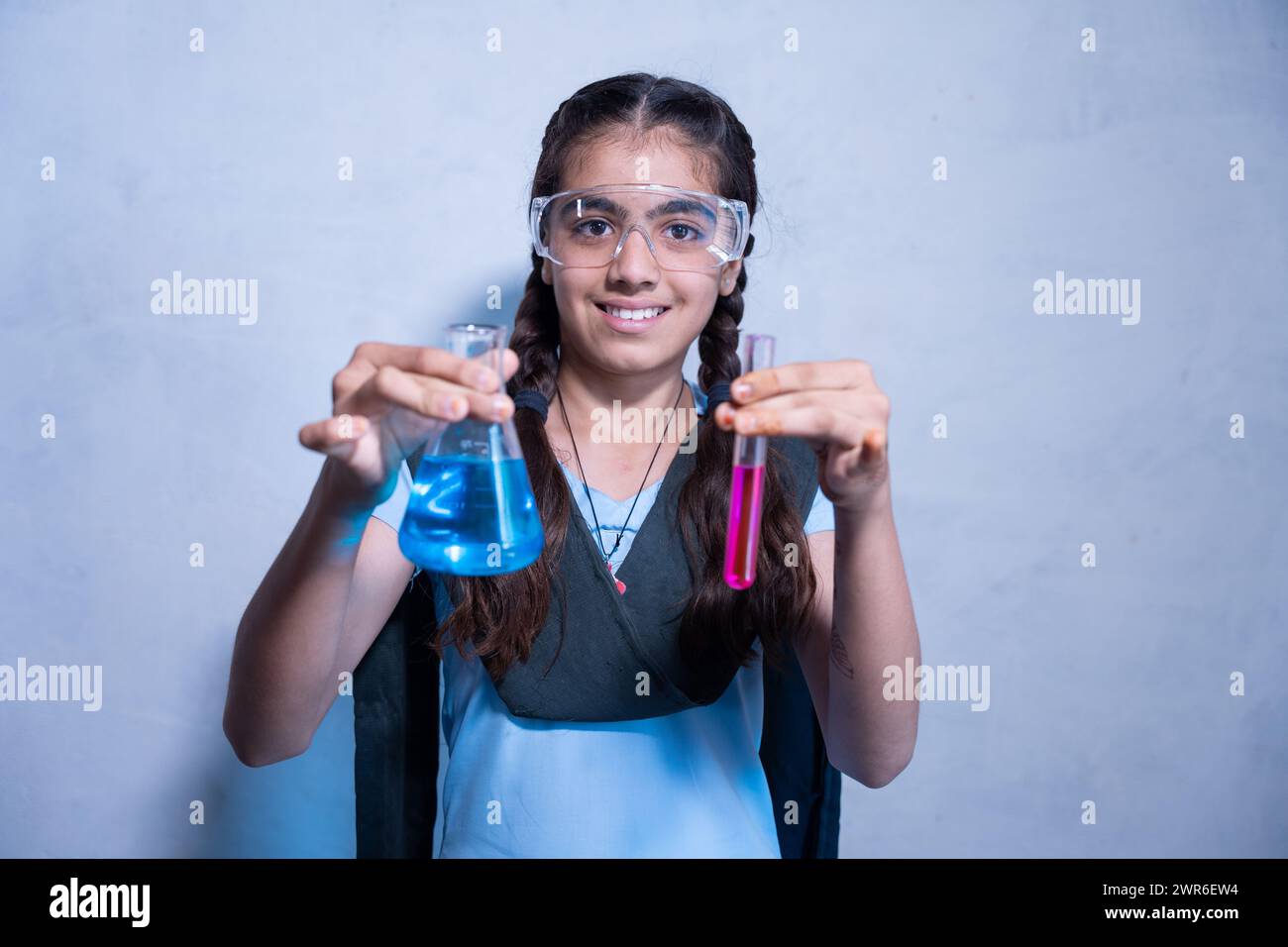 Happy Young Indian girl in school uniform wearing safety lab goggles ...