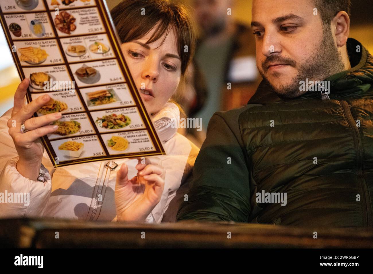 In a cozy restaurant booth, two lovers pore over the menu, their shared ...