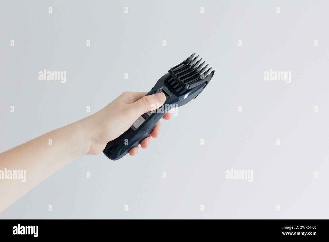 Woman's hand holding electric hair cut machine on white background ...
