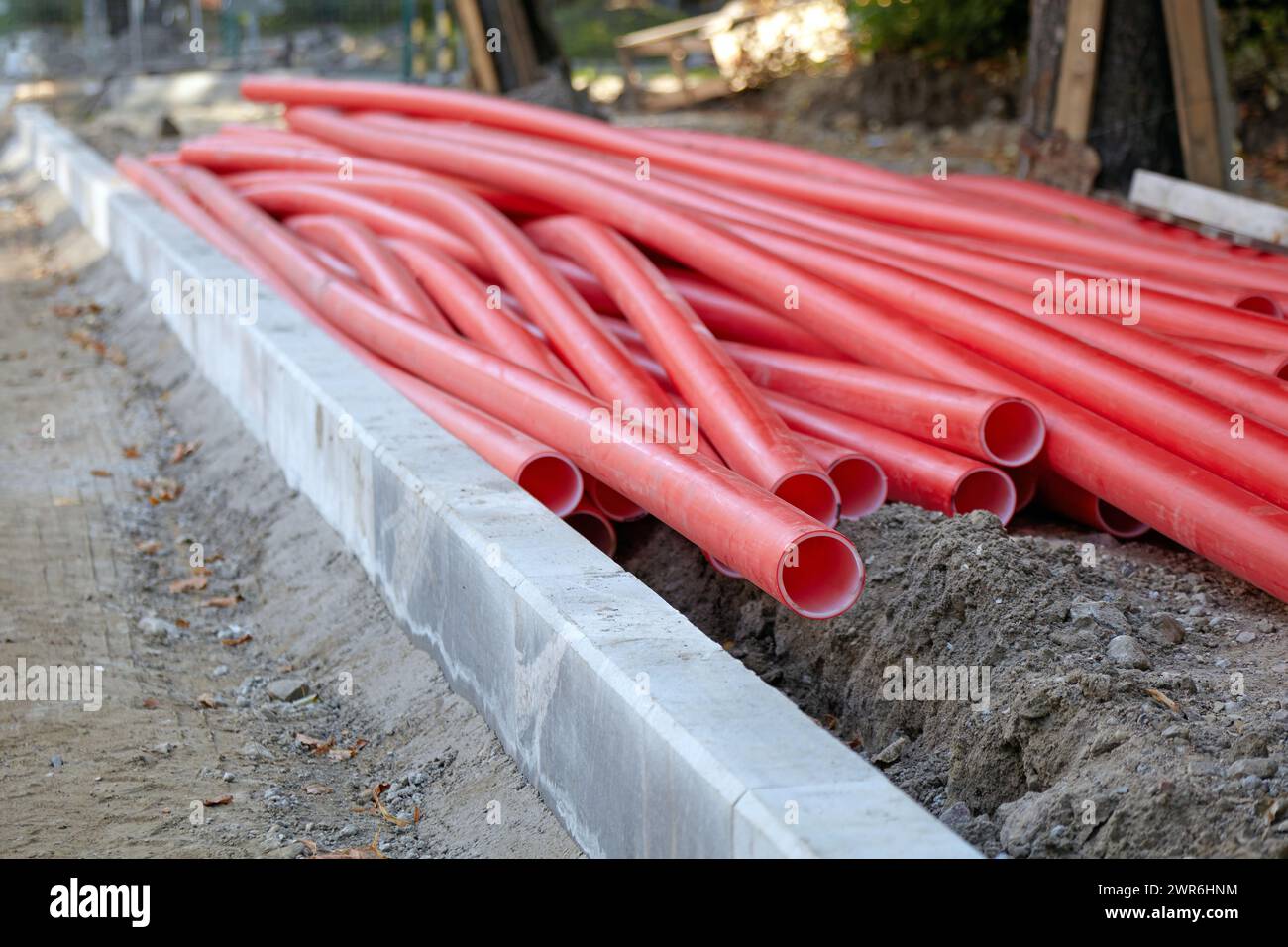 Red plastic utility pipes piled at a road repair site Stock Photo - Alamy