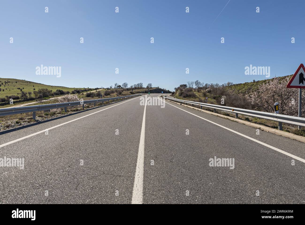 A two-lane road with one lane in each direction with a solid white line ...
