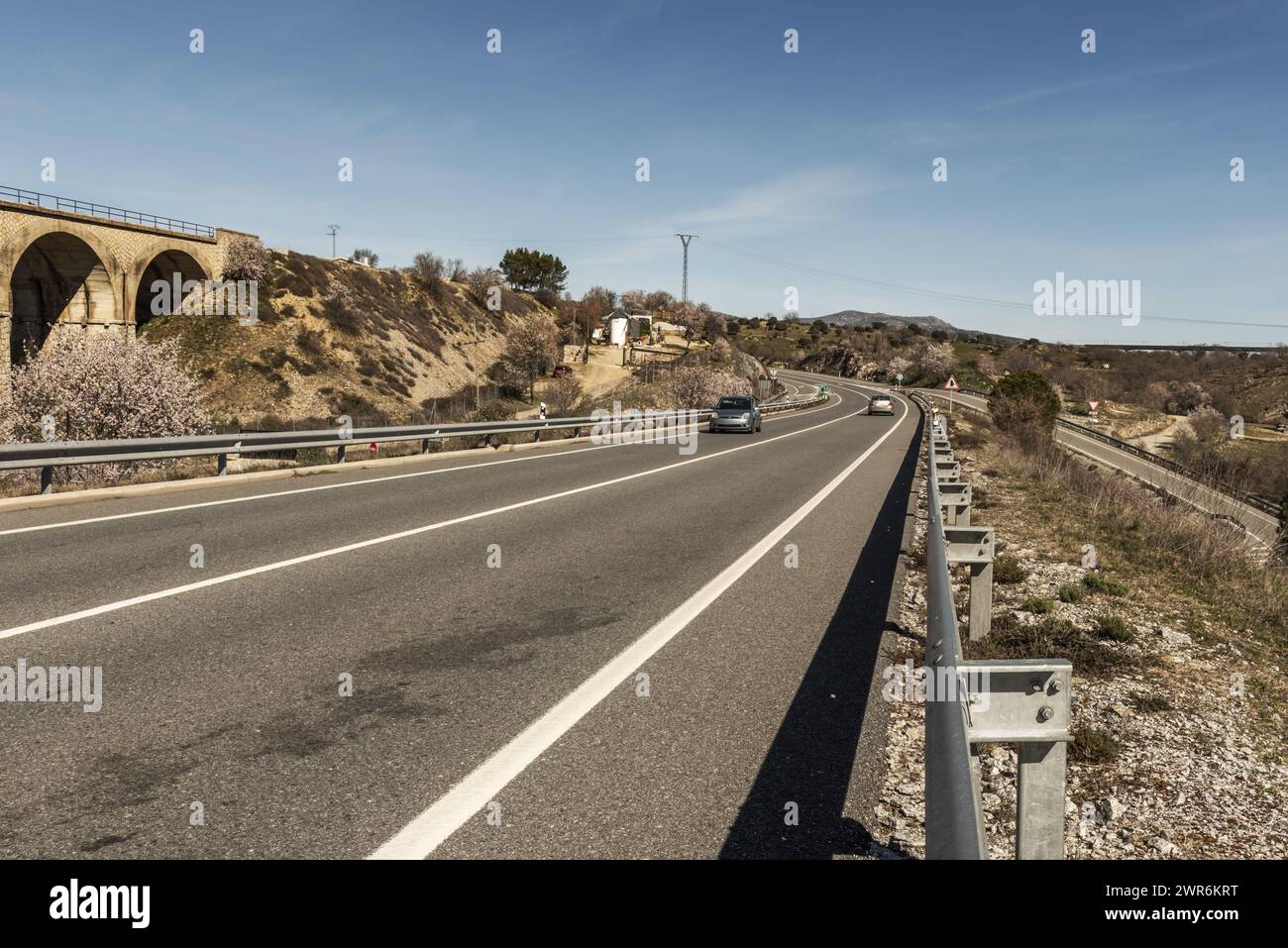 A two-lane road with one lane in each direction with a solid white line ...
