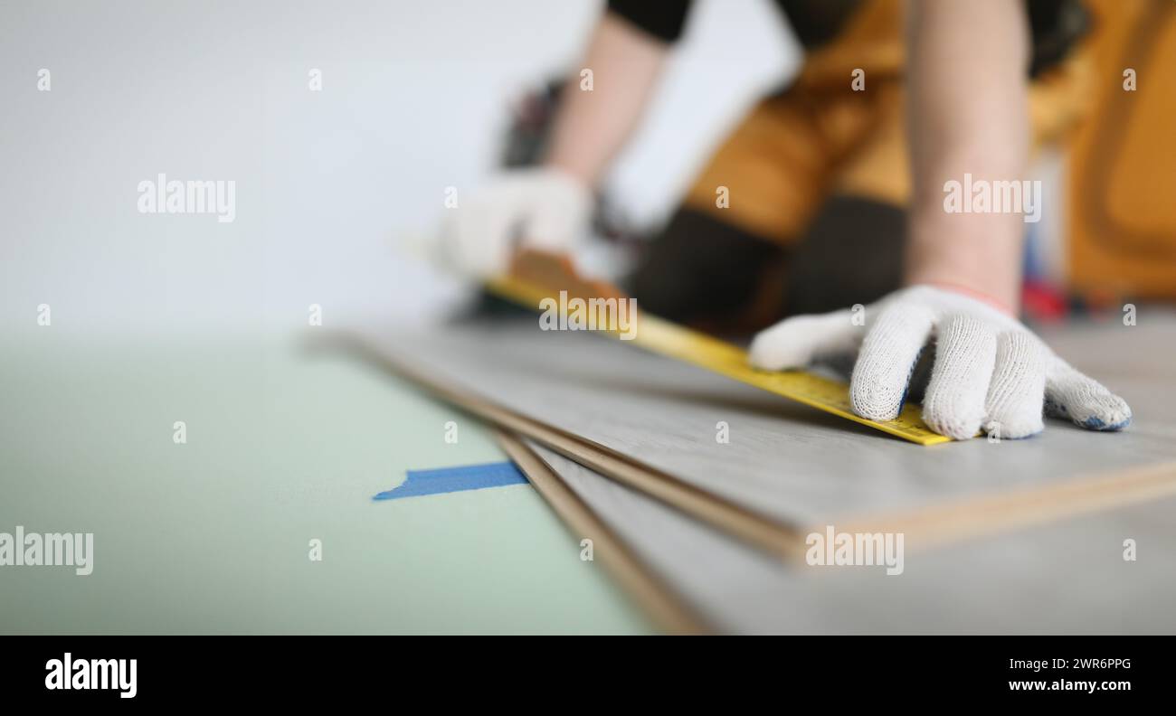 Man builder measuring laminate board with ruler for laying floor ...