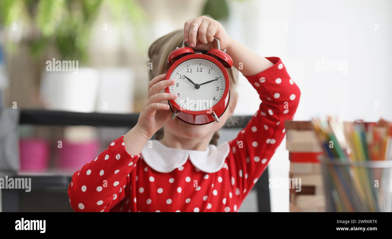 Little girl holding red alarm clock in front of her face Stock Photo ...