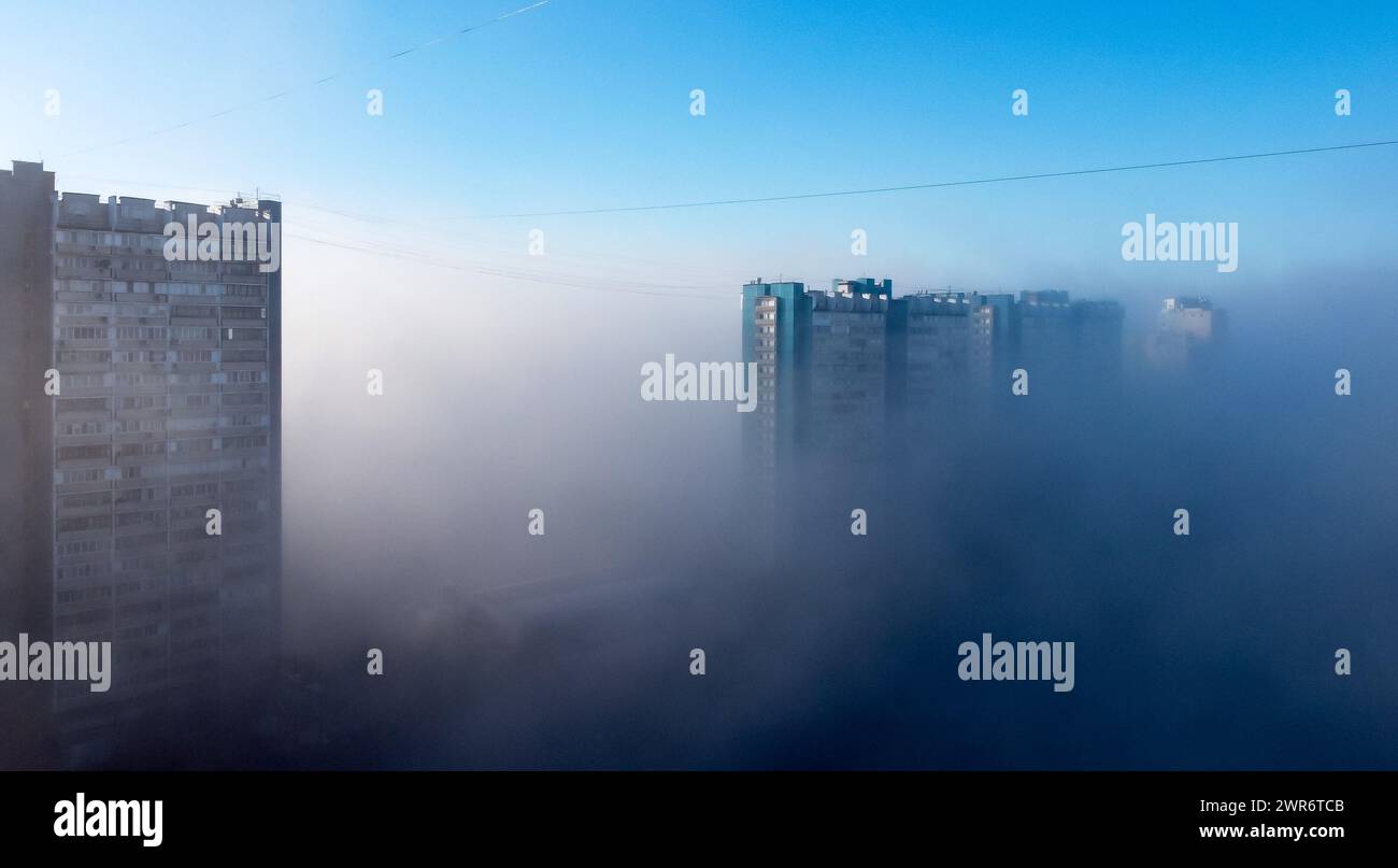 A white-and-blue multi-storey residential building is shrouded in fog ...