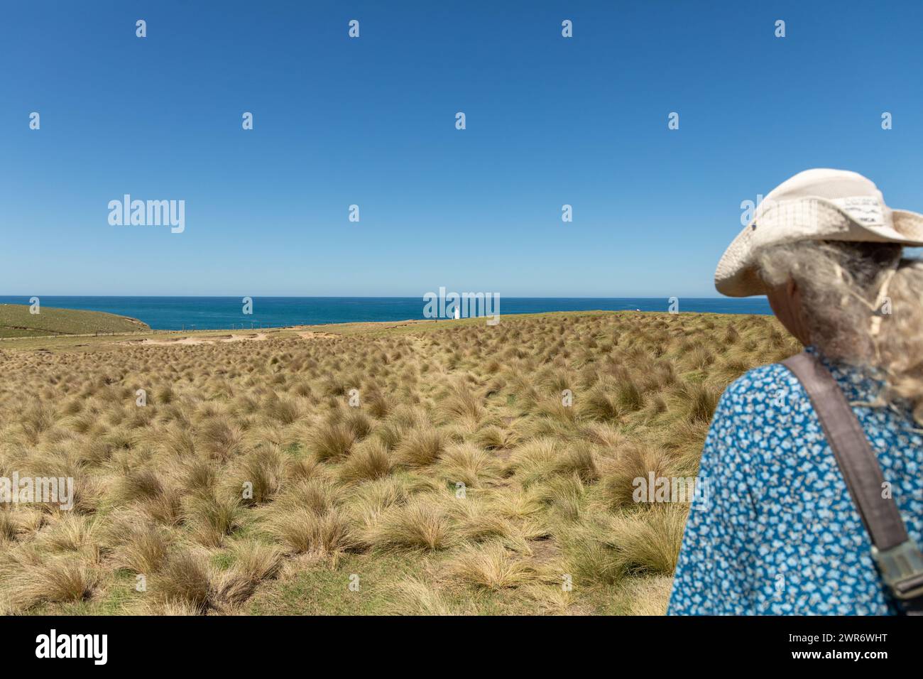 A tourist approaches a beacon at Slope Point, the most southerly point ...