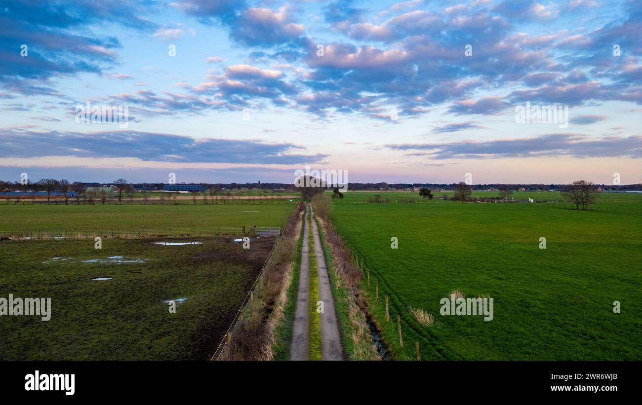 Evening settles over a countryside path cutting through lush fields ...