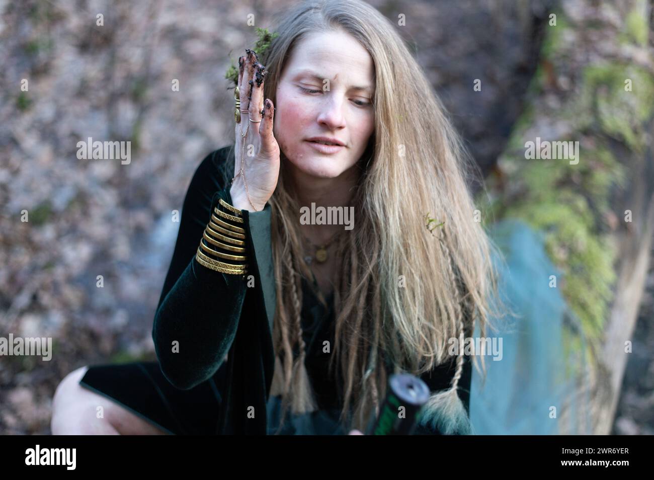 A female shaman performs a nature ritual by smearing her face with ...
