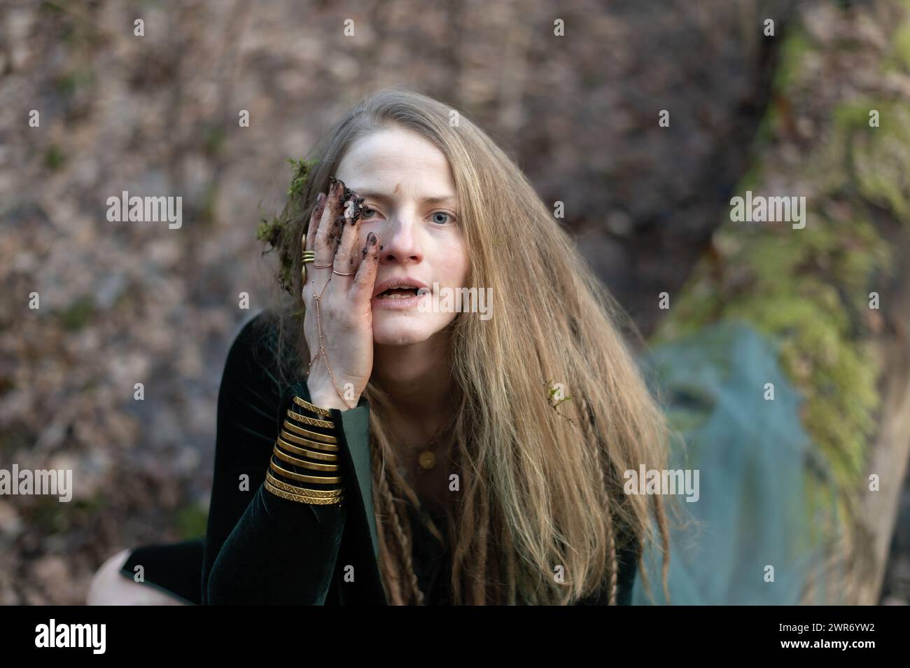 A female shaman performs a nature ritual by smearing her face with ...