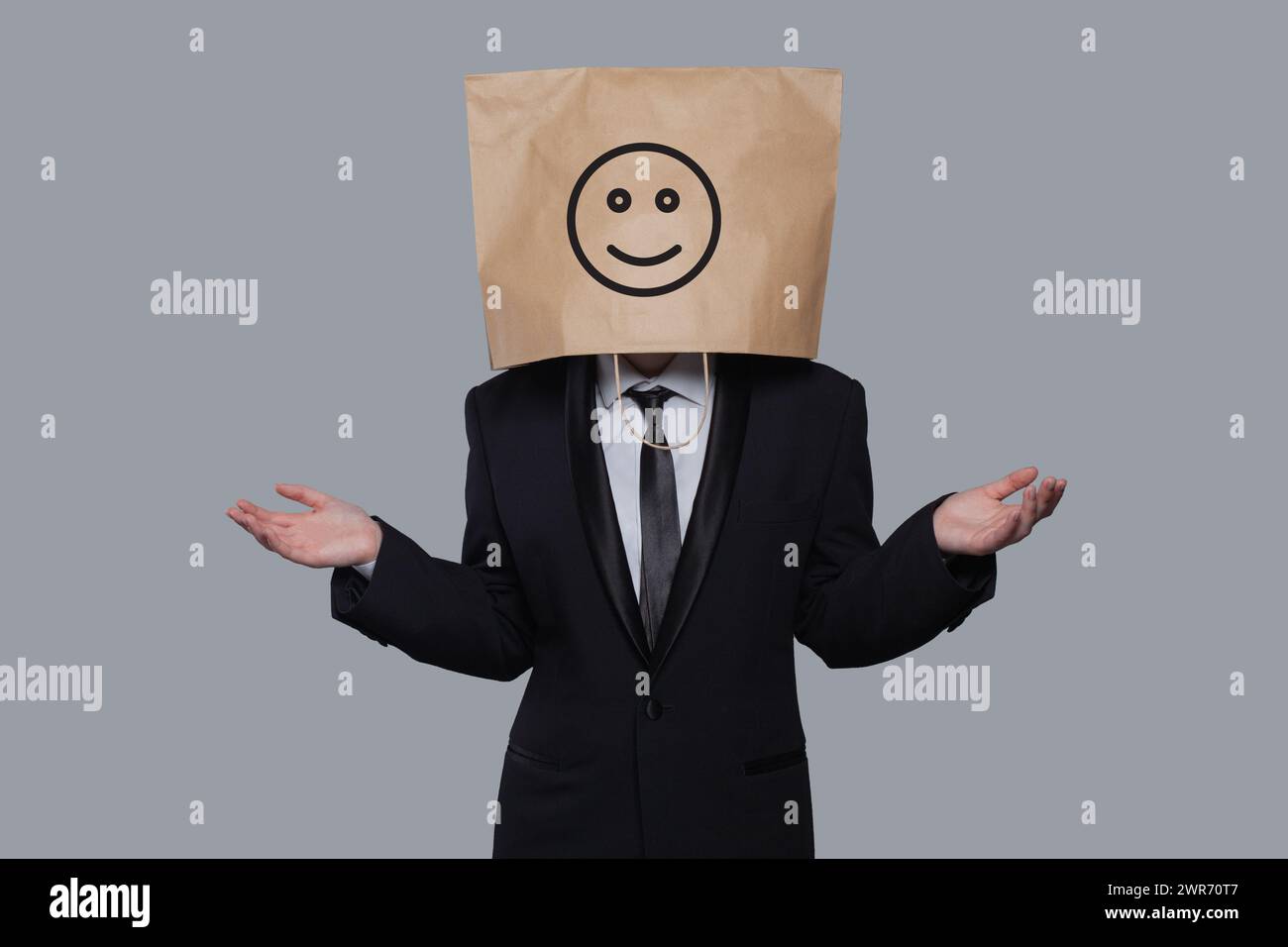 Business person anonymous hiding his head behind happy smile emoticon ...