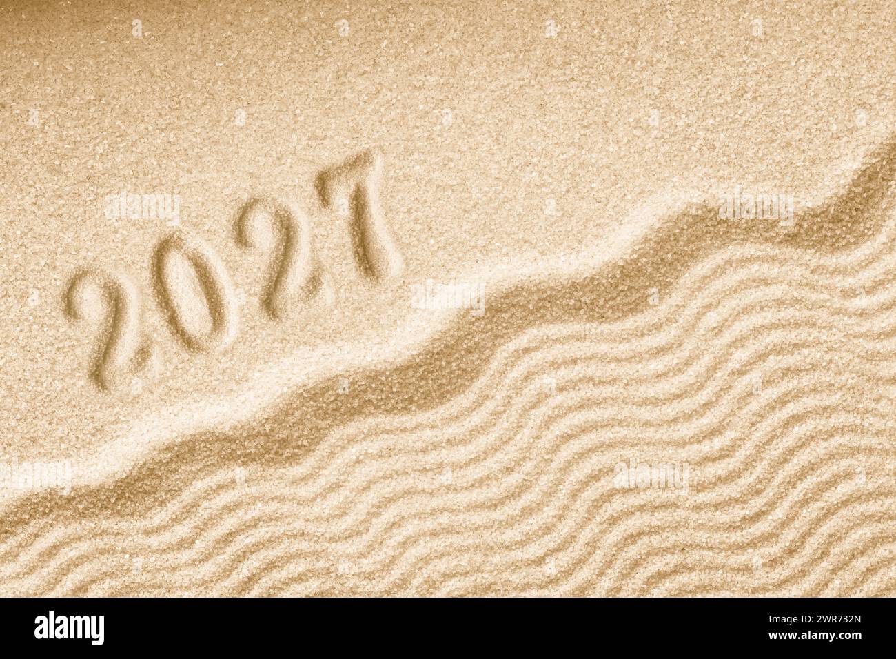 Imprints of numbers 2027 happy new year on a golden sand waves ...