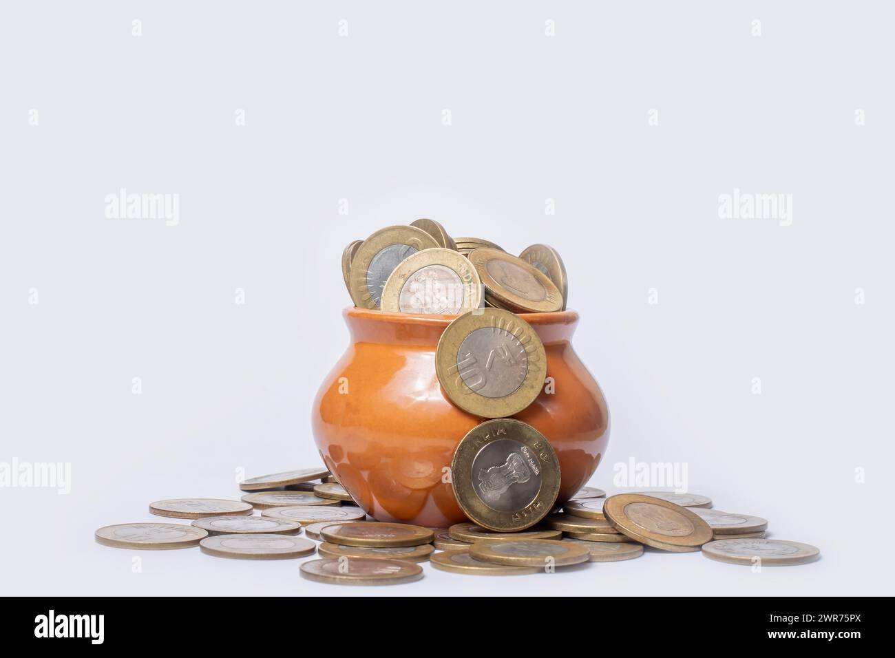 Coins in a clay pot on a white background with copy space. Saving ...