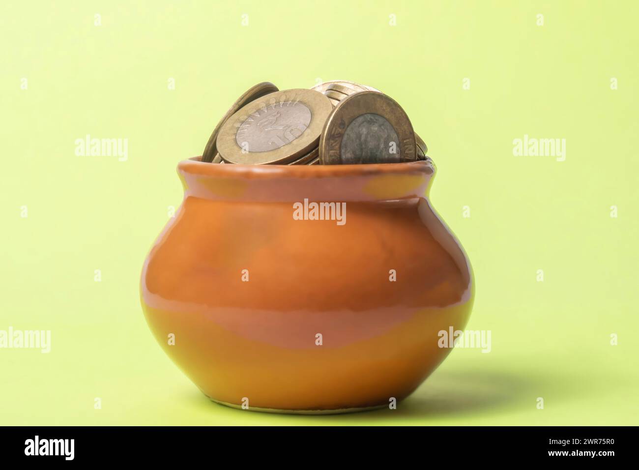 Coins in a clay pot on a green background. saving concept Stock Photo ...
