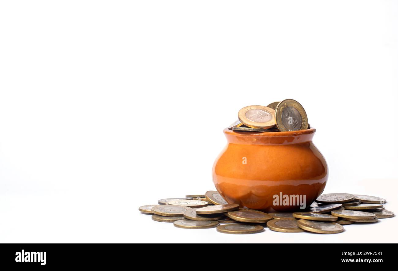 Coins in a clay pot on a white background with copy space. Saving ...