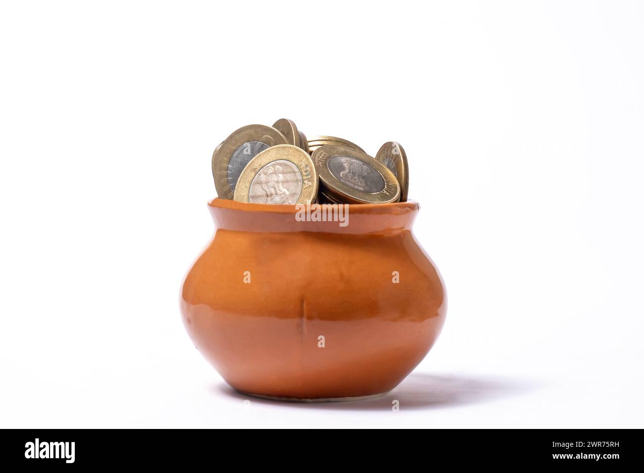 Coins in a clay pot on a white background. Saving money concept Stock ...