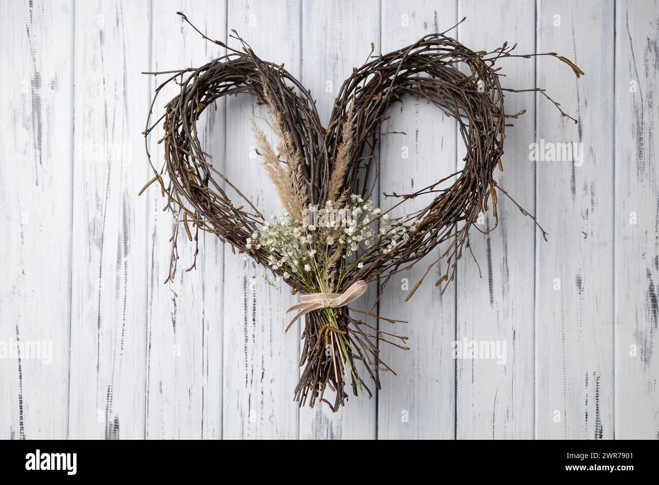 Wicker heart shaped wreath of birch branches hanging on aged wooden ...