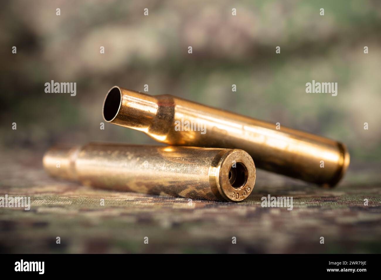 Two rifle bullets cartridges on green military camouflage fabric ...