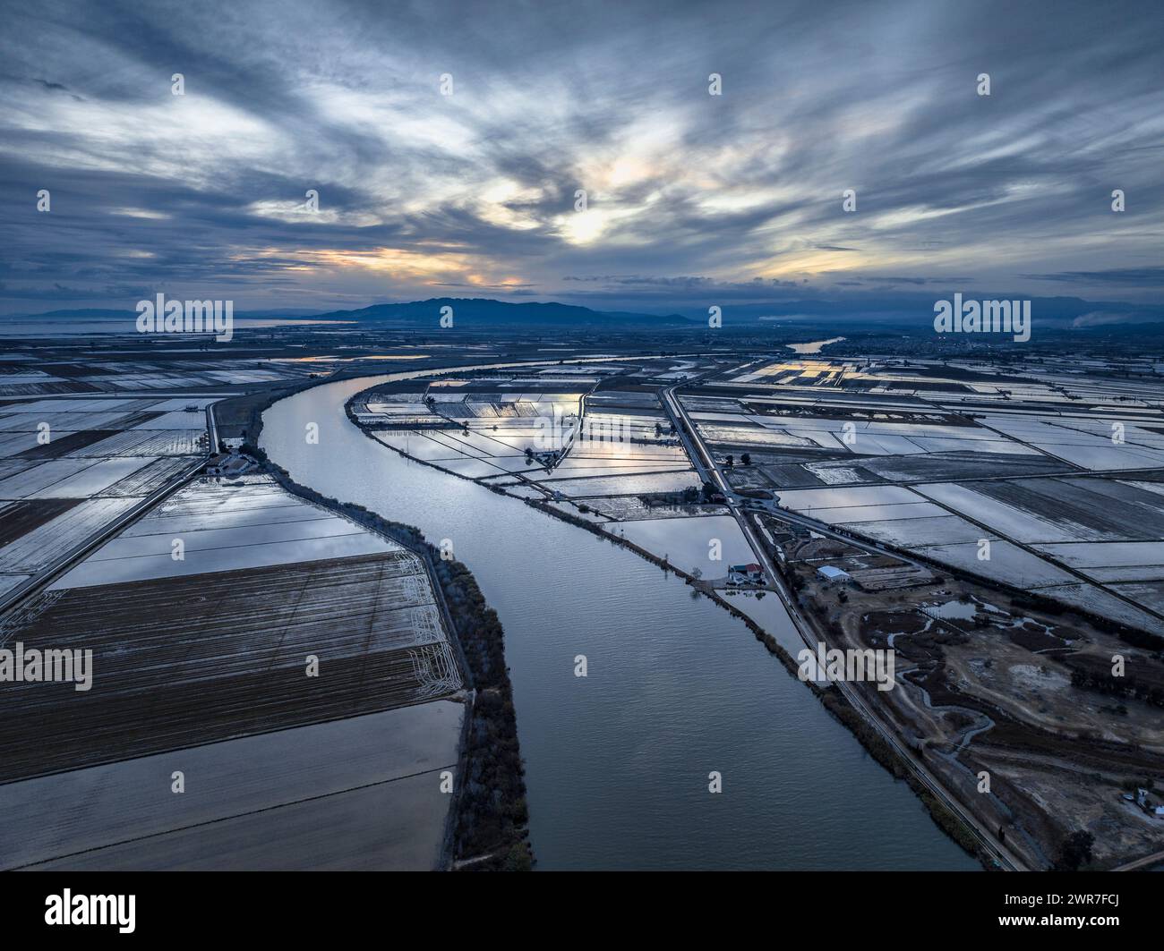 Sunset between rice fields flooded with water and the Ebro River in the ...