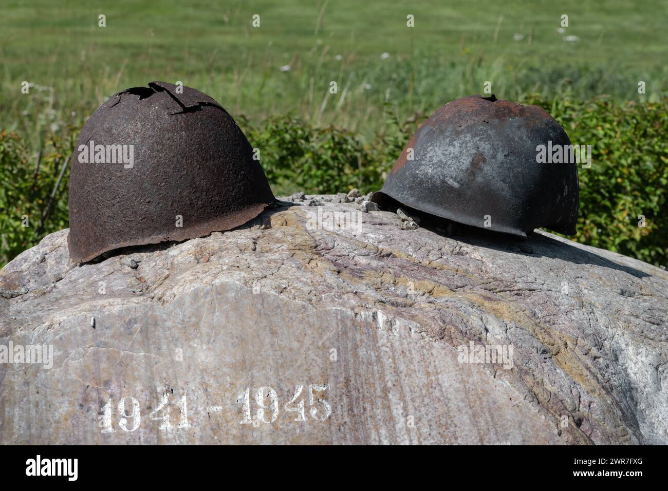 Two old rusty military helmets with holes lie at the memorial world war ...