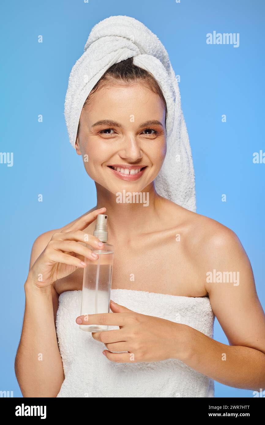 happy woman with towel on head and bottle of body spray smiling at ...