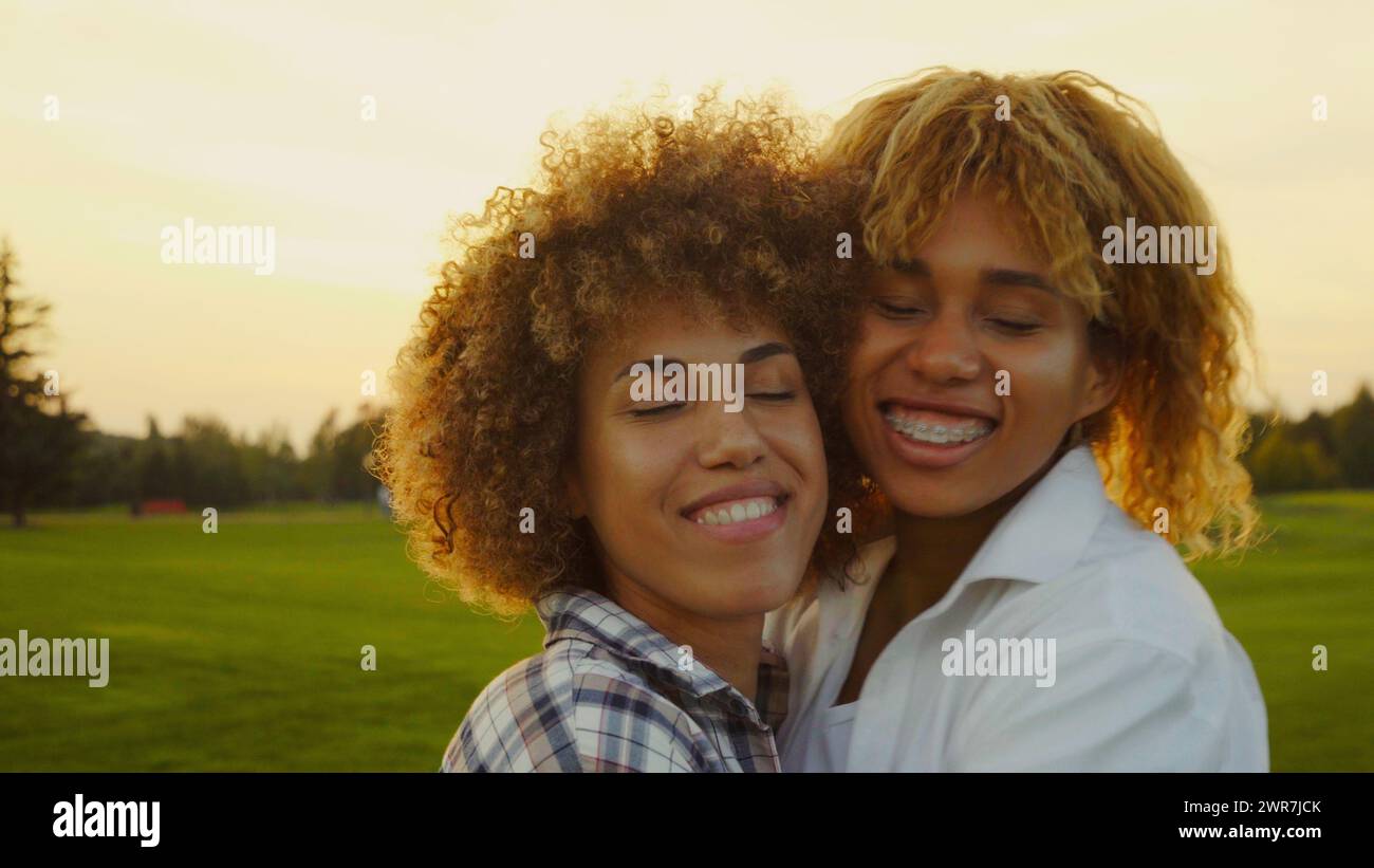 Young Afro girlfriend sisters with afro hair hugging on the park ...