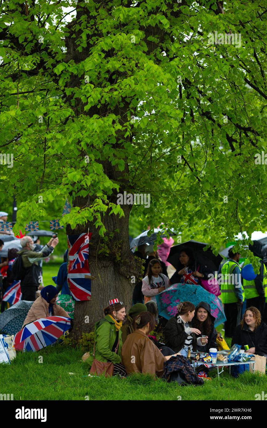 People shelter from rain under a tree as they gather to view the ...