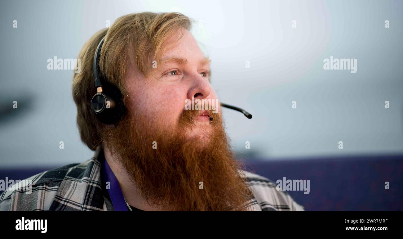 Alternative pierced male contact centre working listening to a call ...