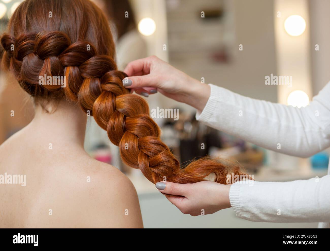 Beautiful, with long, red-haired hairy girl, hairdresser weaves a ...