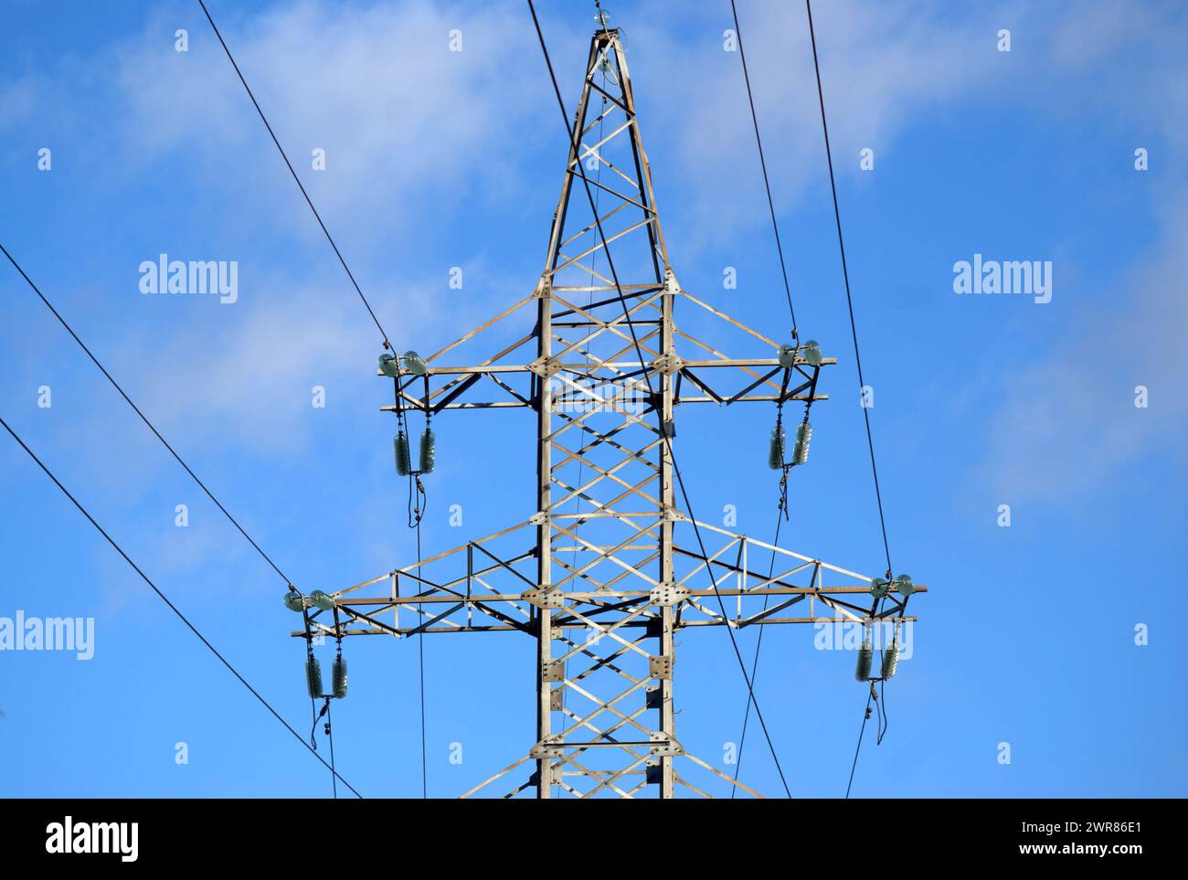 Top section of high-voltage power line metal prop on blue sky with ...