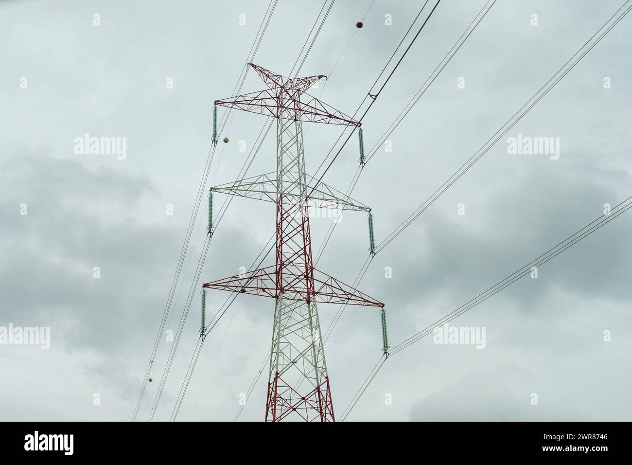 A high voltage power line towers against a clear blue sky, carrying ...
