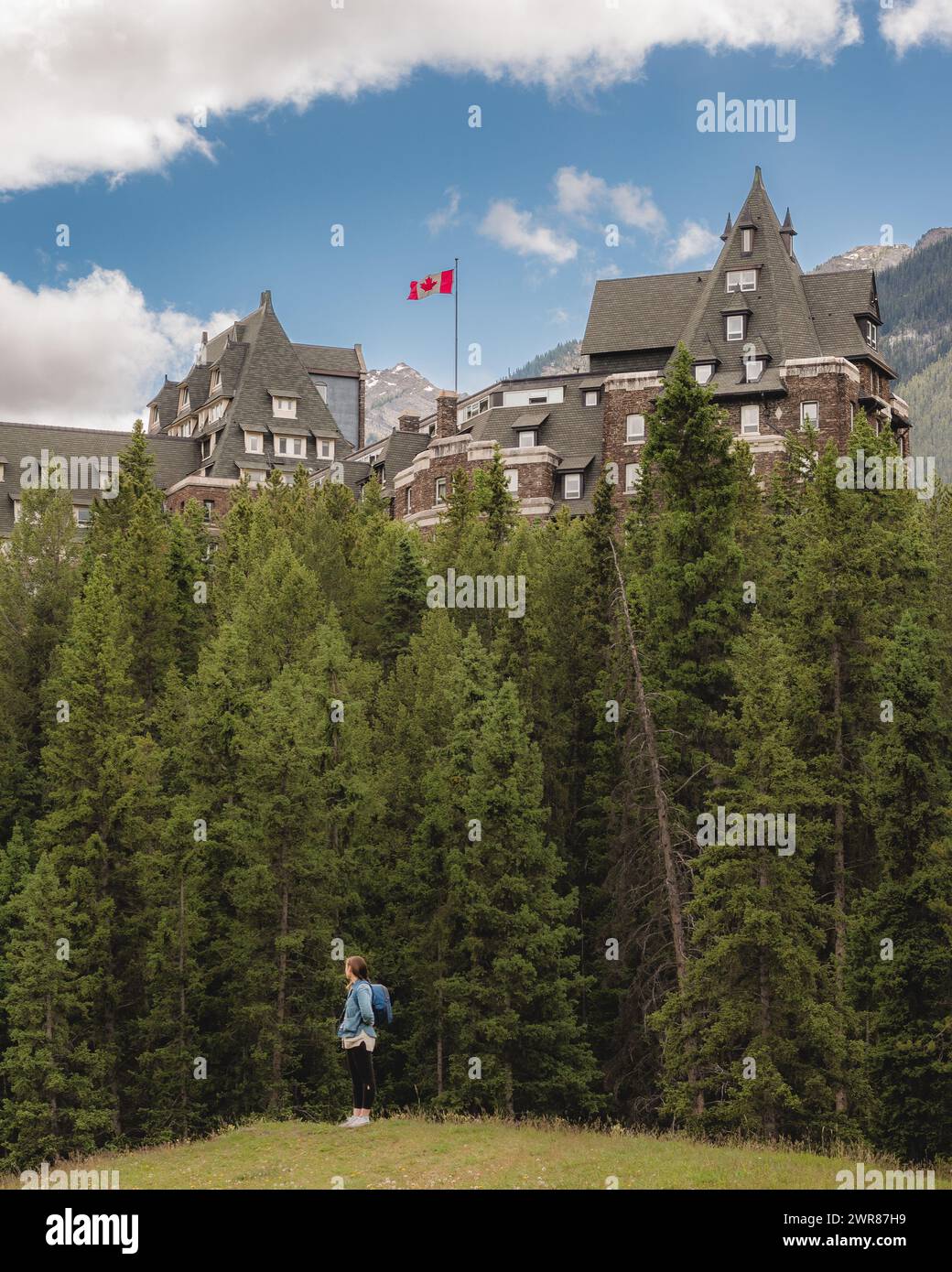 My wife standing in the foreground of some tall pine trees and the ...