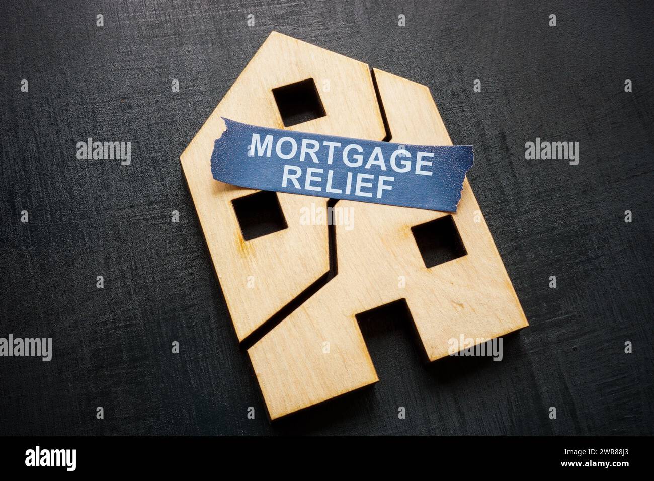Mortgage relief. Broken house model and fastening tape Stock Photo - Alamy