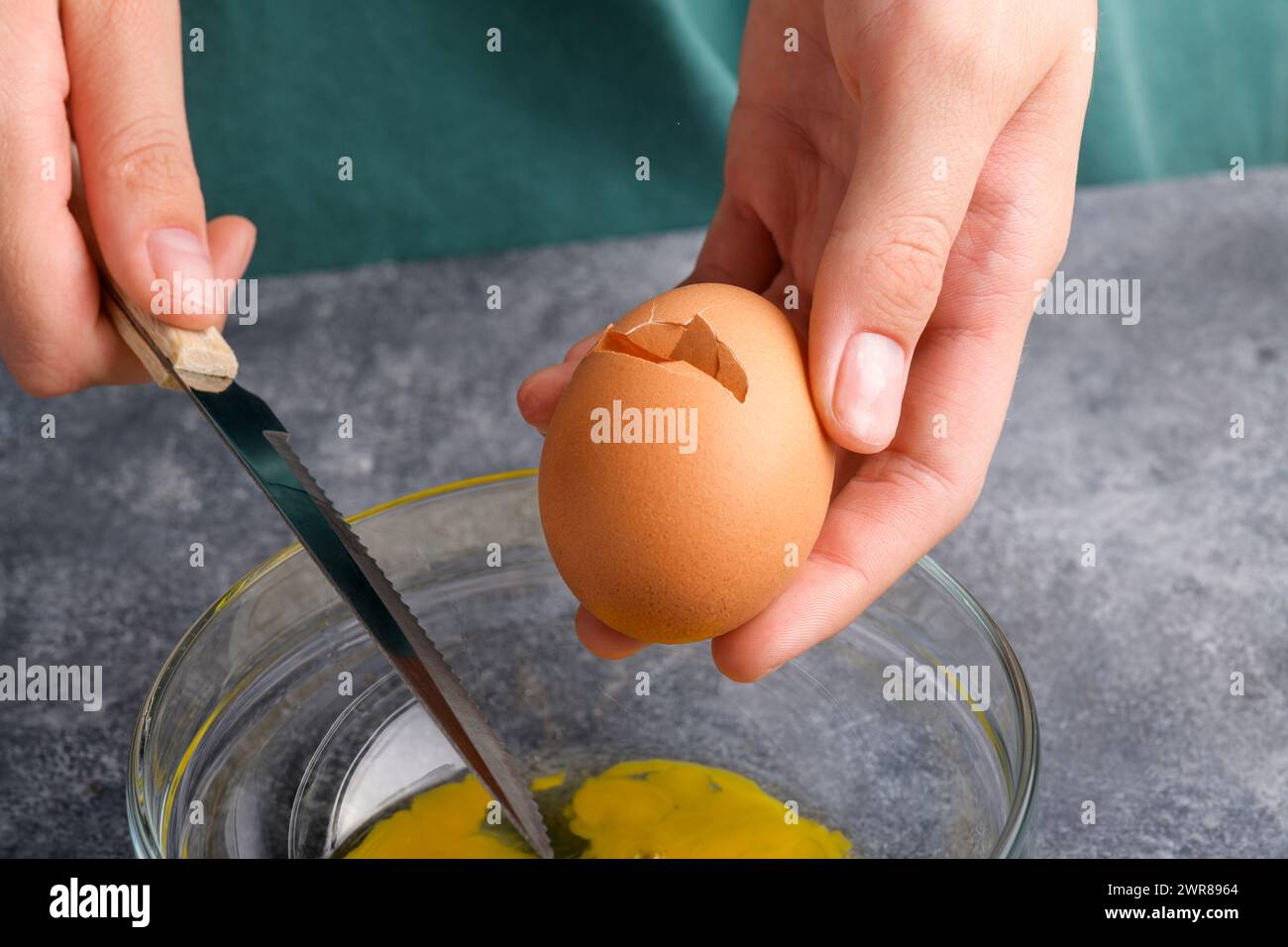 A cracked egg in the hand, close up. A woman's hand cracking an egg ...