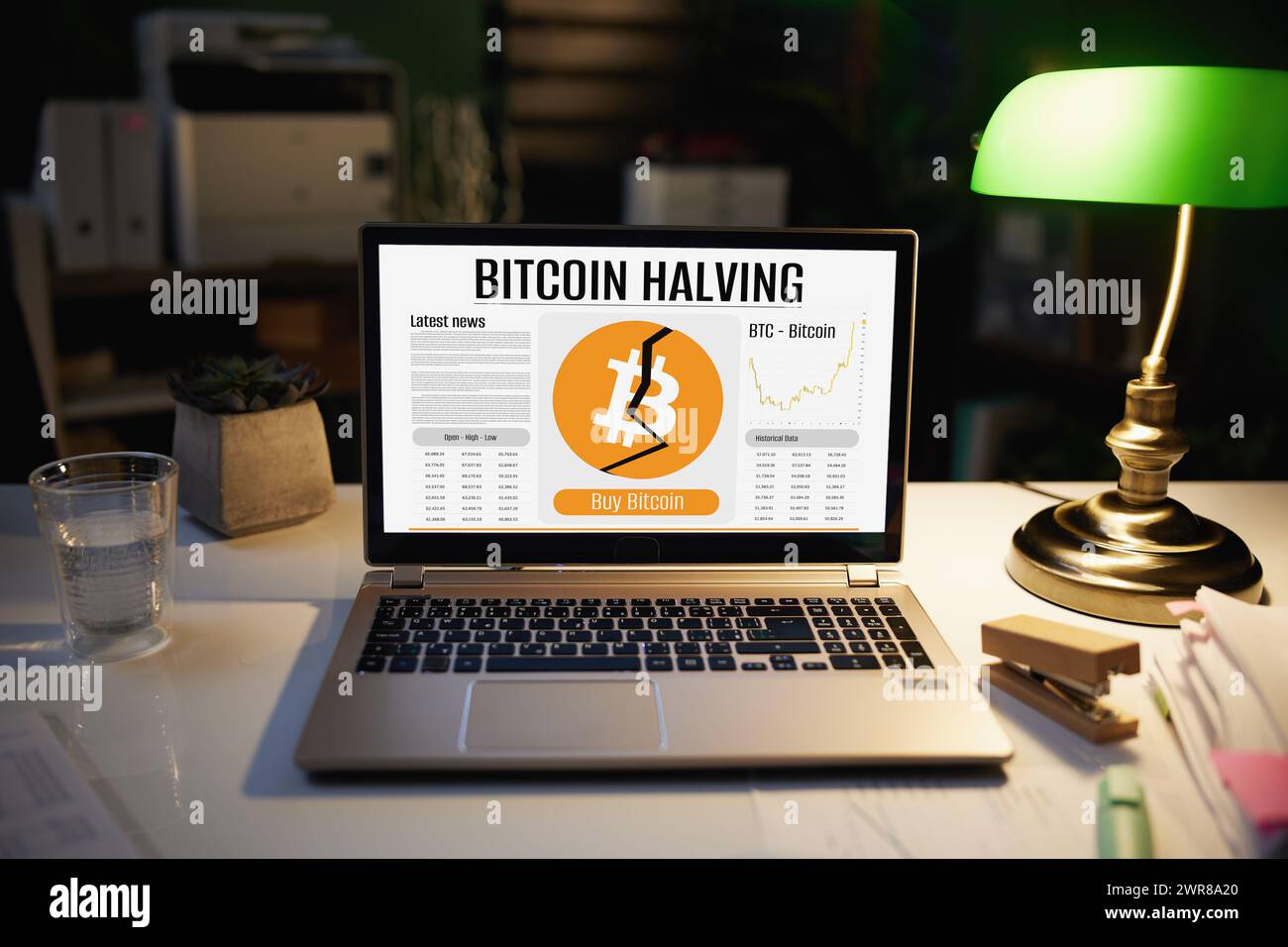 desk with laptop with bitcoin halving screen at night in the modern ...