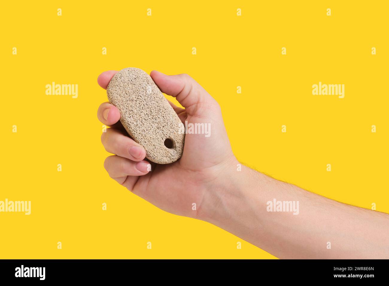 Pumice stone for cleaning feet and heels, in hand on yellow background ...