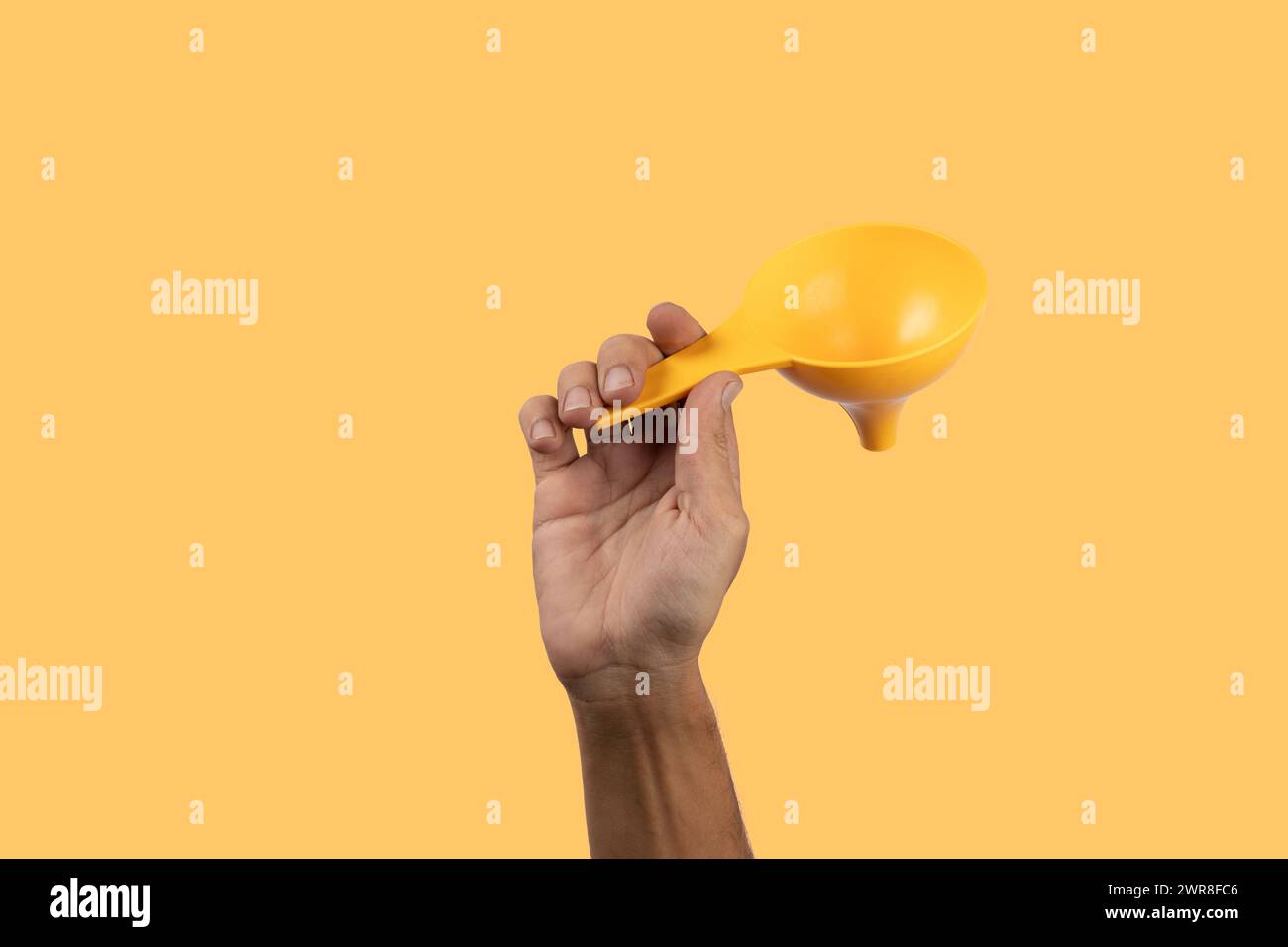 Black male hand holding a yellow kitchen funnel isolated, yellow ...