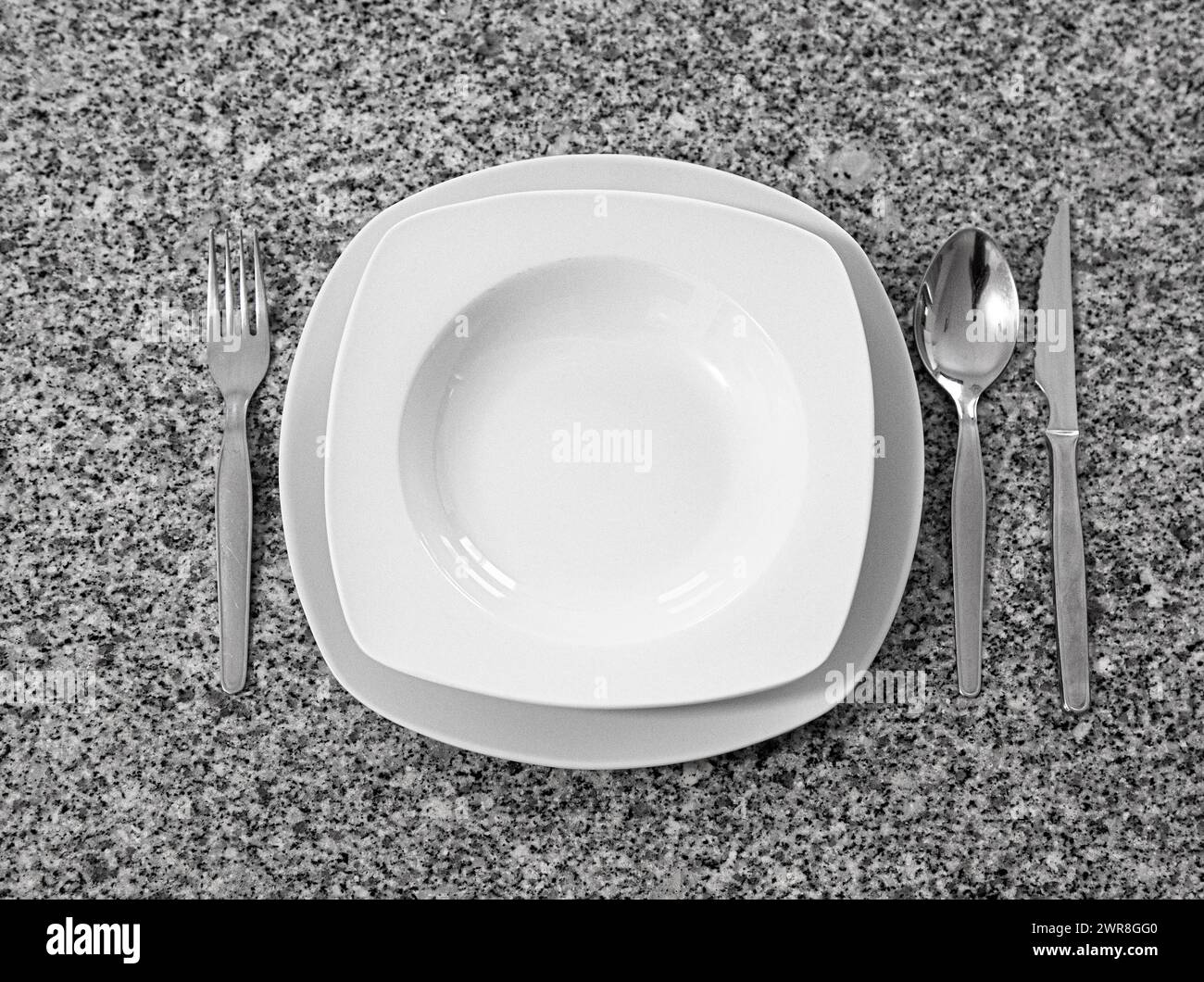 Blank flat white plate, fork on gray stone table, top view. Mock up ...