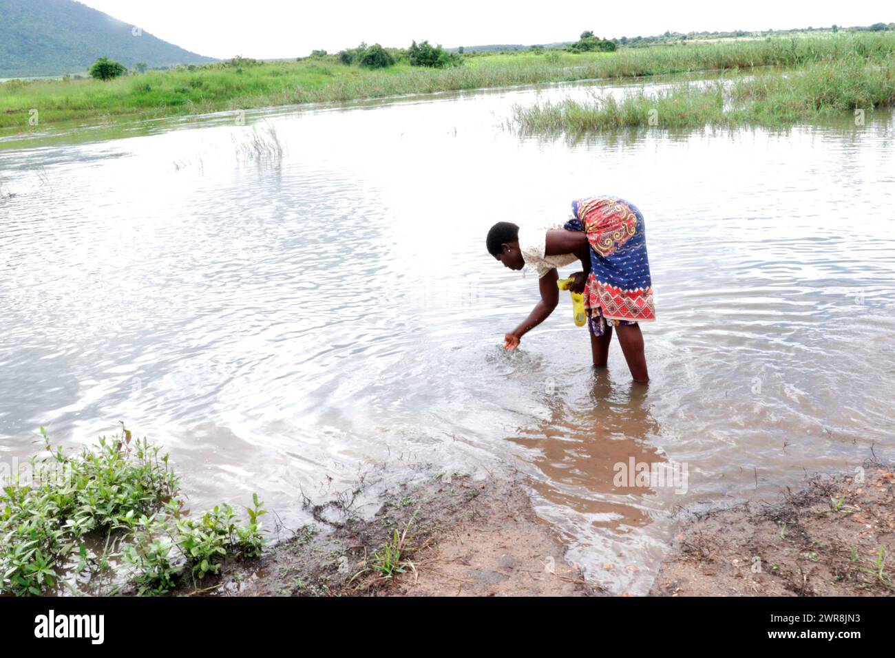 A woman is seen in Bua river cleaning her sandals and washing her hands ...