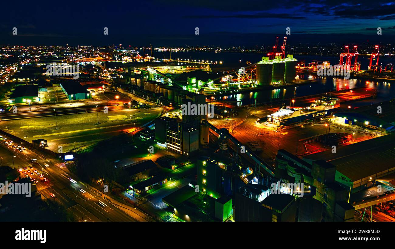 Nighttime aerial view of an industrial port with illuminated cranes and ...