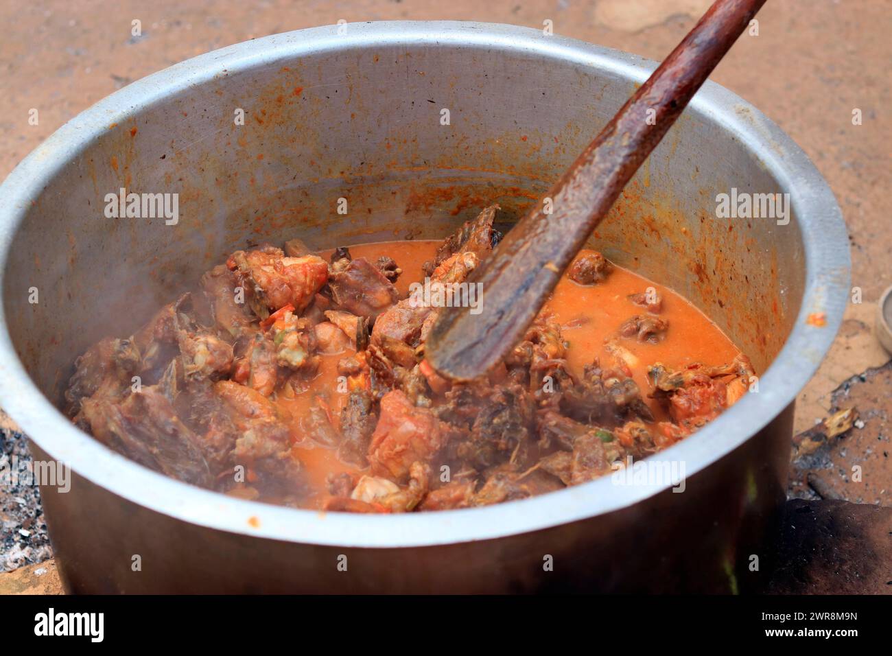 A pot of chicken stew is seen on an open fire. The meal was ready to be ...