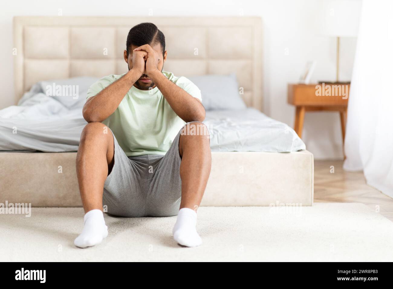 Upset black man sitting on floor at bedroom, crying Stock Photo - Alamy