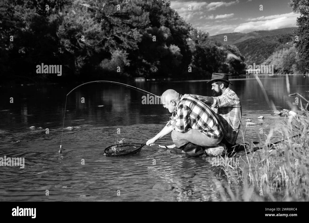 Father and adult son fishing lakeside. Handsome men relaxing outside ...